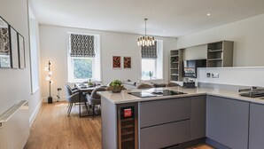 Uma cozinha moderna com ilha central, eletrodomésticos embutidos e área de jantar com lustre.