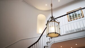 Uma escadaria imponente com balaústres brancos e um candelabro.