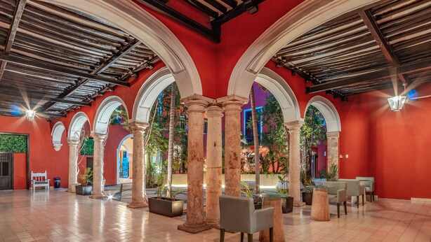 Amplo espaço interno com pé direito alto, colunas em arco e piso em azulejos.