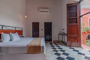 Quarto com cama, mesa de cabeceira, aparelho de ar condicionado e piso xadrez.