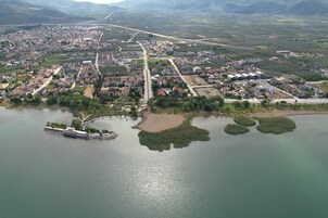 Vista aérea de uma cidade costeira com um porto de recreio, áreas residenciais e uma ponte ao fundo.