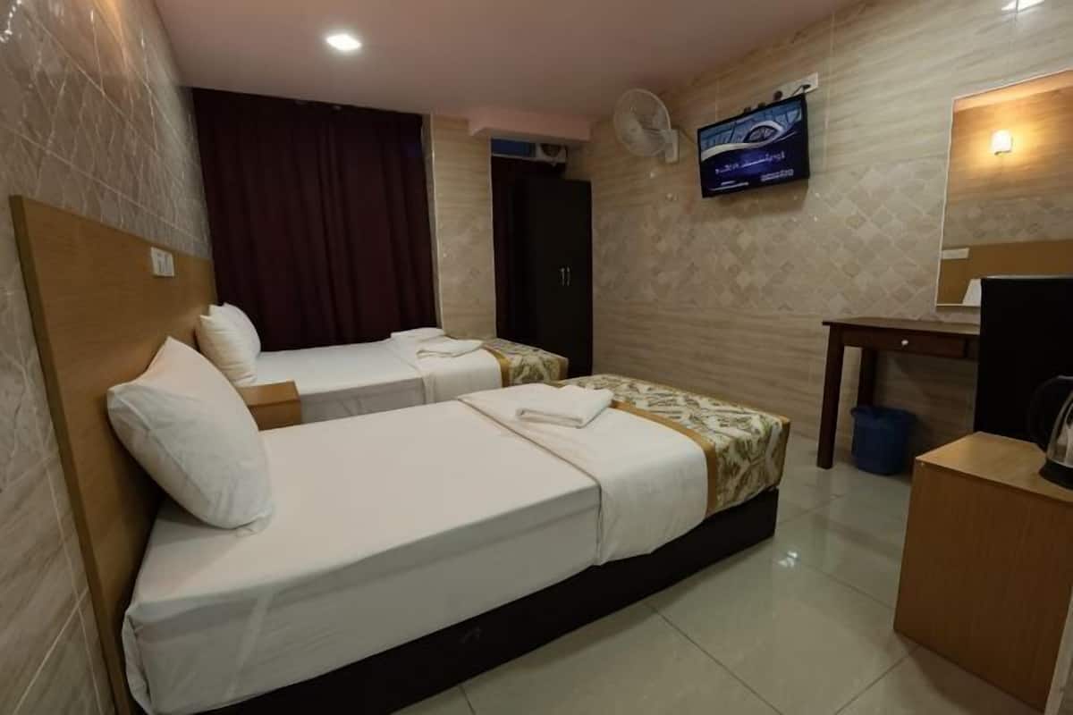 Quarto de hotel com duas camas, televisão, escrivaninha e uma cadeira.