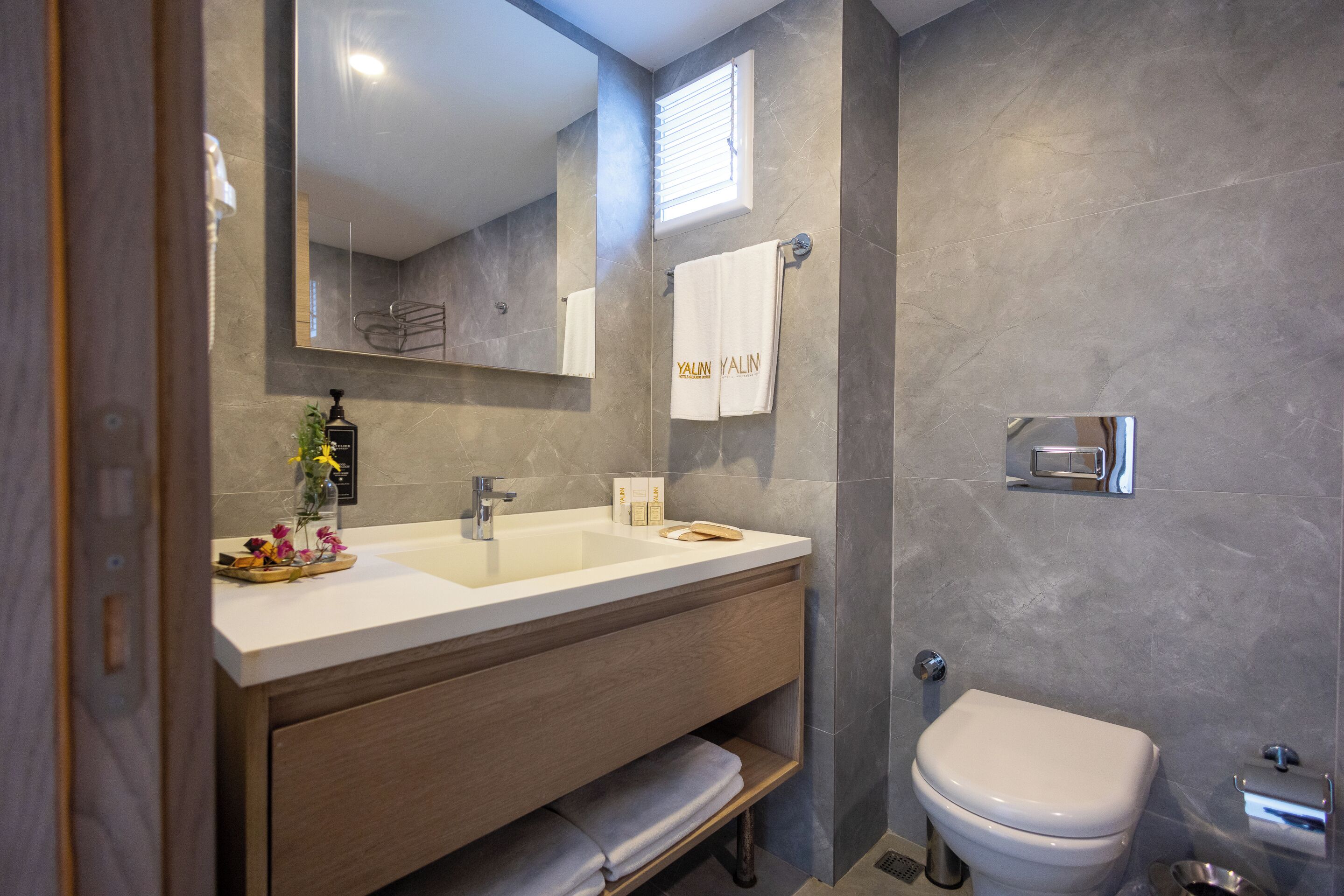 Uma casa de banho moderna com lavatório duplo, sanita e espelho grande.