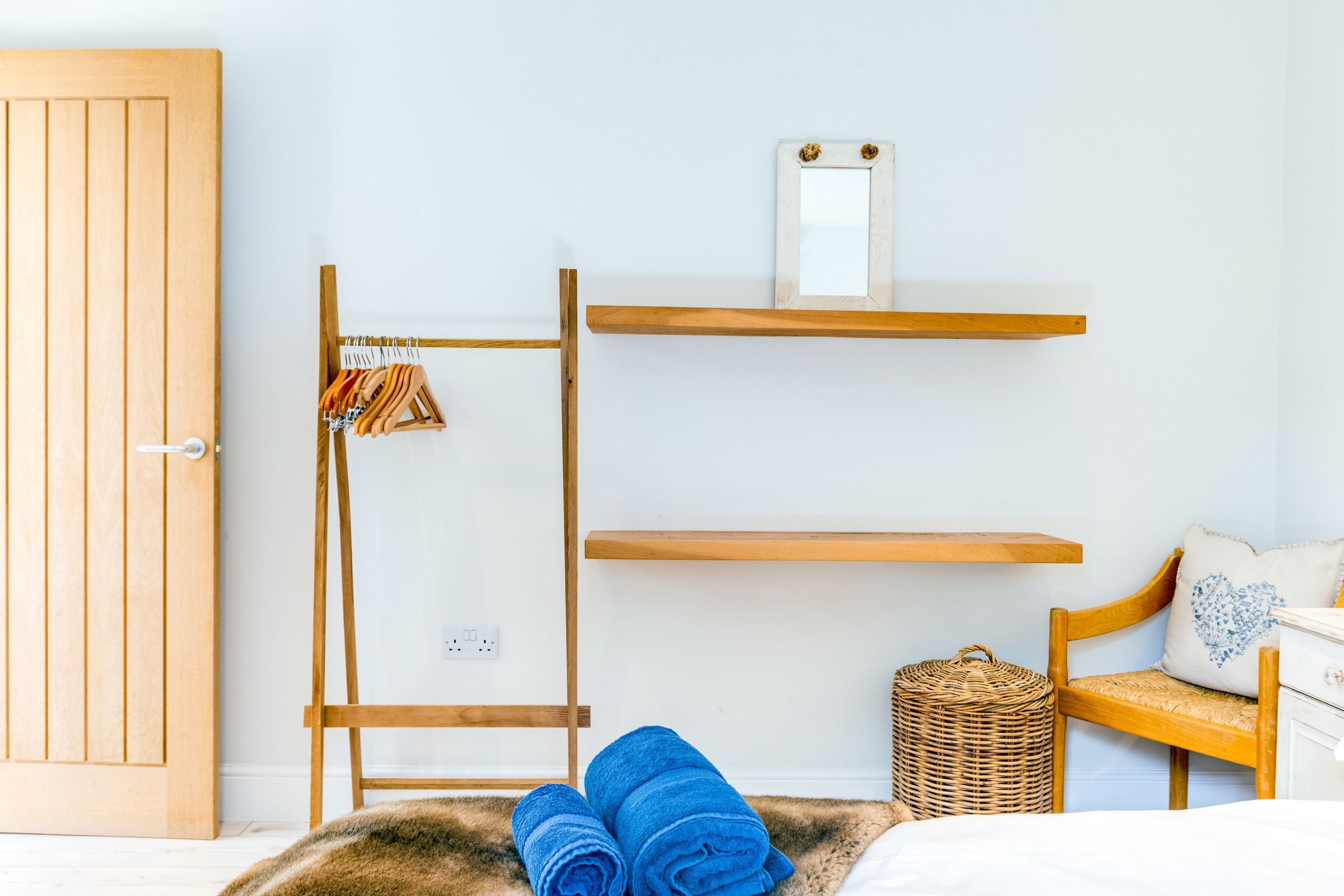 Quarto com guarda-roupa de madeira, escada de madeira, espelho e cama com tapete de pele.