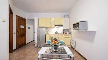 Uma cozinha compacta com mesa, cadeiras e eletrodomésticos básicos.