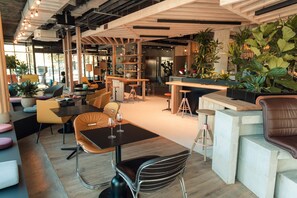 Uma área de estar moderna com assentos, um bar e diversas plantas.