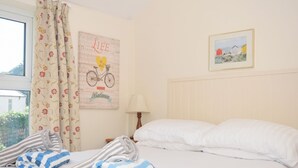 Quarto com cama, toalhas listradas, arte de parede com tema de bicicleta, abajur e quadro na parede.