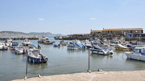 Uma marina com vários barcos atracados, um cais e um edifício com uma placa.