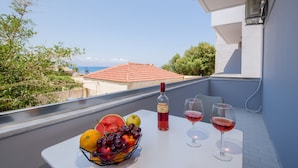 Varanda com mesa posta, com frutas, uma garrafa de vinho e duas taças.