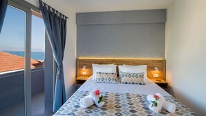 Quarto de hotel com uma cama grande, duas mesas de cabeceira e vista para o mar.