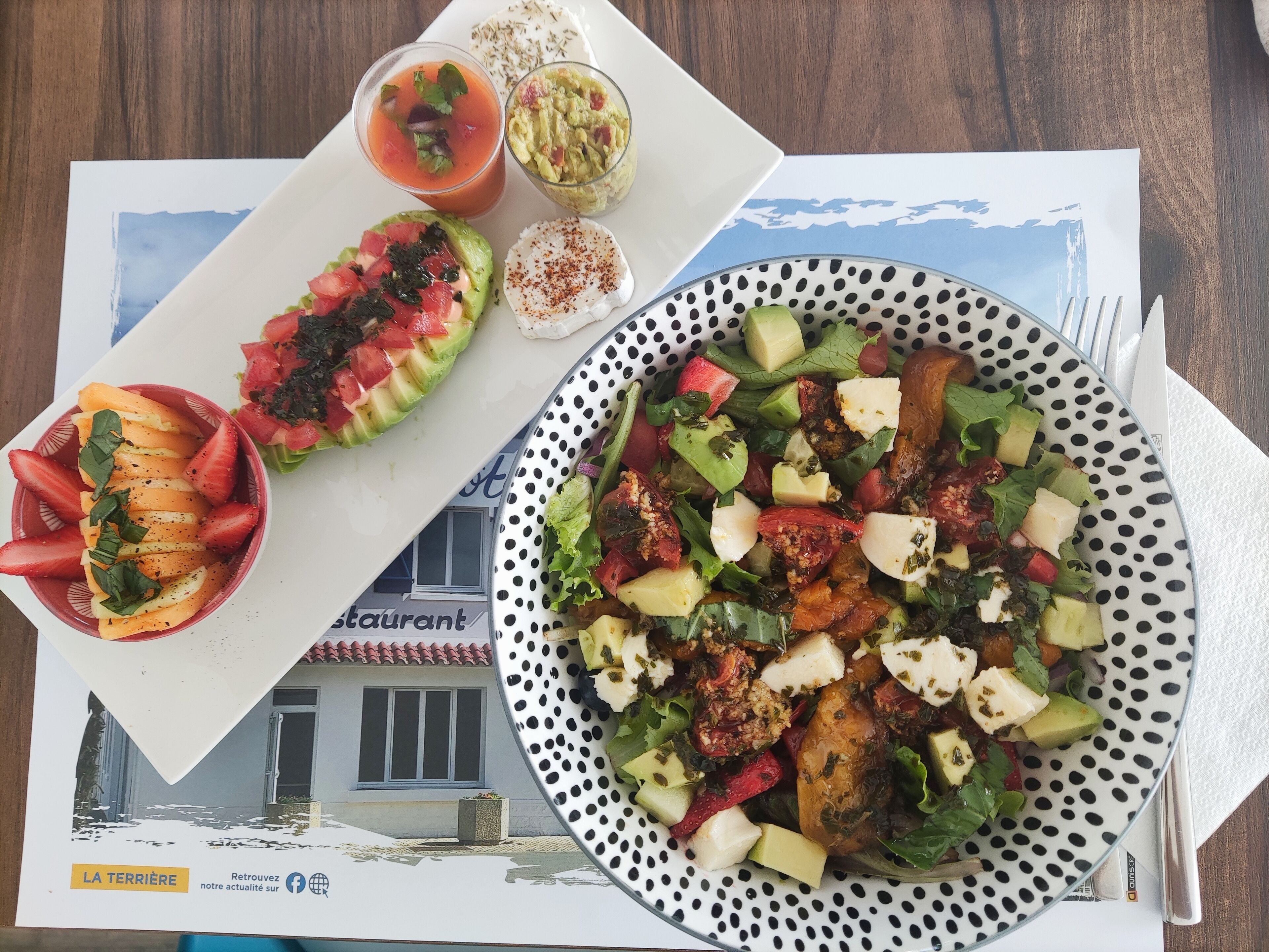 Uma mesa com diversos pratos, incluindo uma salada, frutas e uma sobremesa.