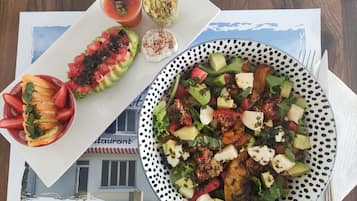 Uma mesa com diversos pratos, incluindo uma salada, frutas e uma sobremesa.
