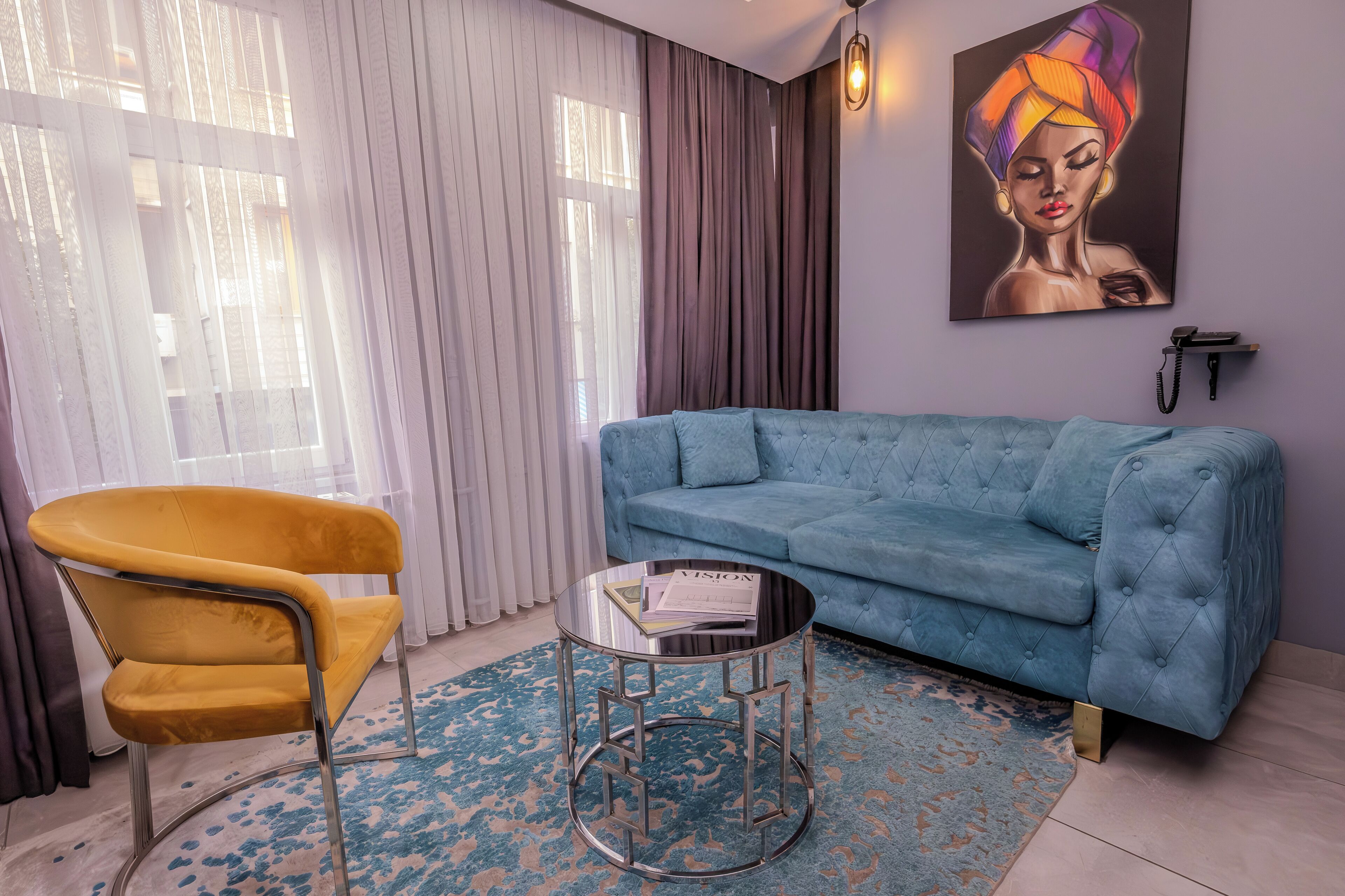 Uma sala de estar moderna com um sofá azul, uma poltrona amarela e uma pequena mesa redonda.