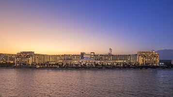 Um hotel grande com vários andares e varandas, localizado à beira de um corpo d'água.