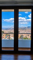 Quarto com uma grande porta de vidro deslizante que dá para uma varanda com vista para a cidade.