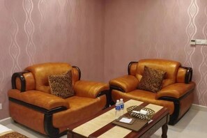 Quarto com dois sofás de couro, uma mesa de centro e parede estampada.