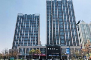 Um edifício moderno com vários andares, possivelmente um hotel ou prédio de escritórios, com uma entrada destacada e sinalização.