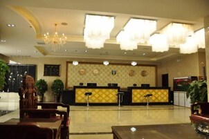 Um saguão de hotel com balcão de recepção, área de estar e um candelabro.