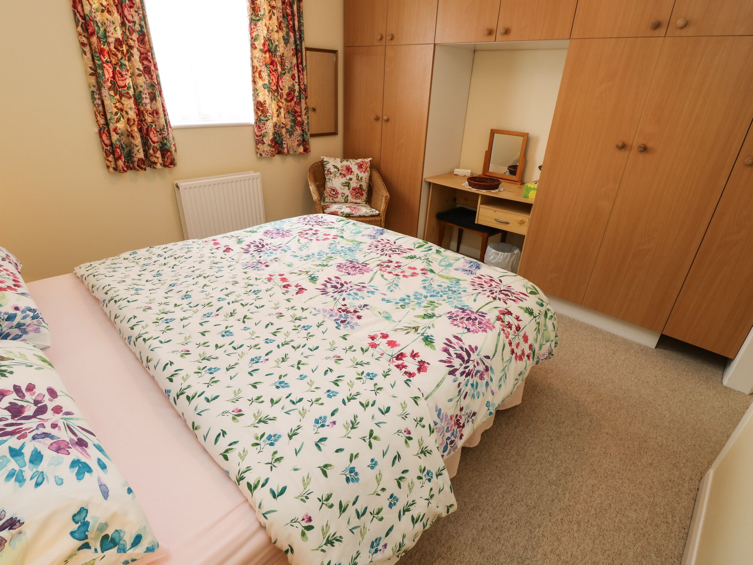 Quarto com cama, cadeira, escrivaninha e guarda-roupa.