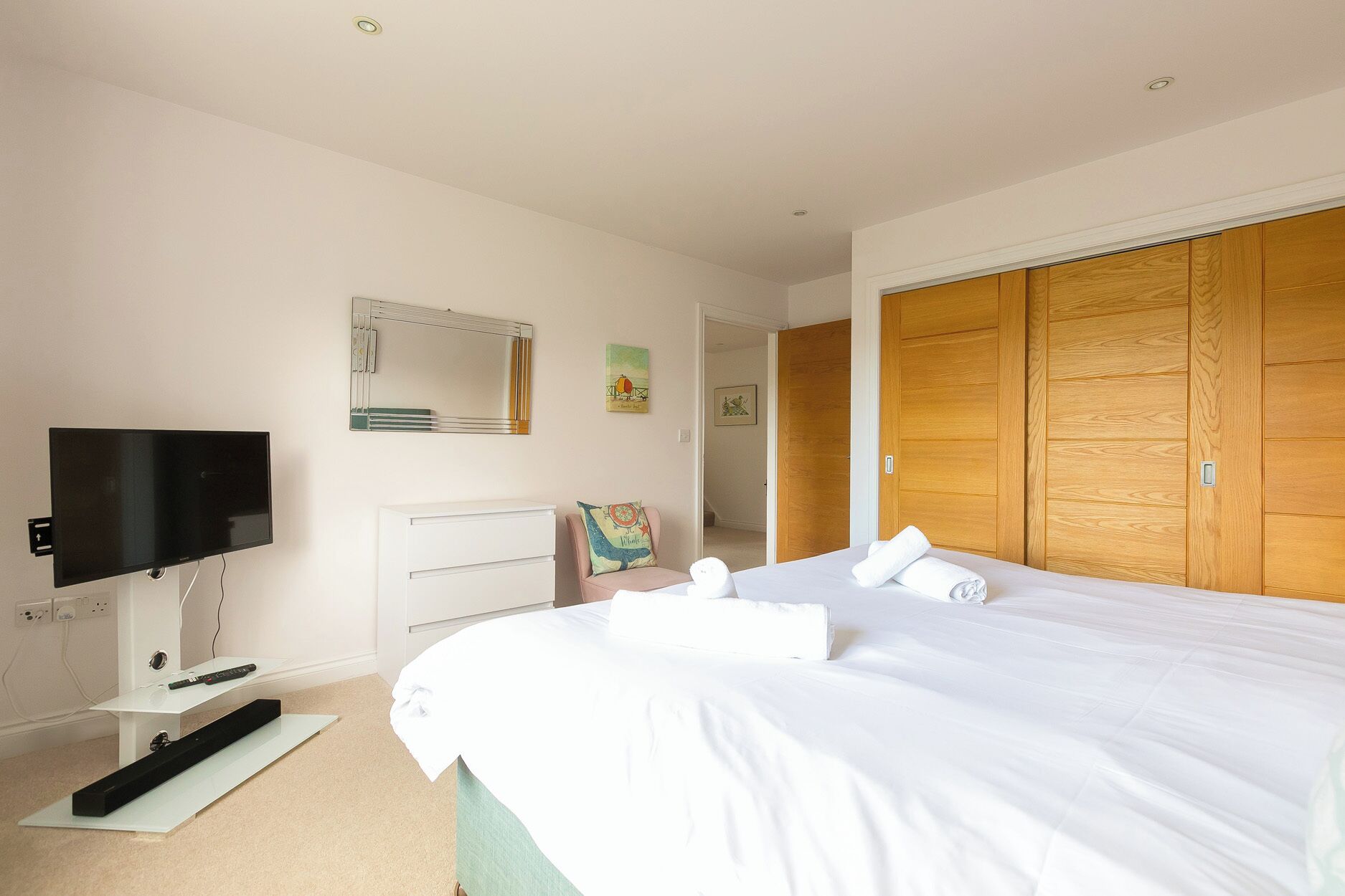 Quarto com cama, televisão, escrivaninha e guarda-roupa.