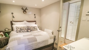 Um quarto bem organizado, com uma cama, abajures, um relógio e uma decoração de cabeça de veado na parede.