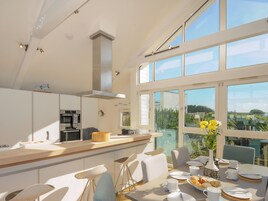 Cozinha moderna com uma ilha grande, eletrodomésticos embutidos e área de jantar com mesa posta para o café da manhã.