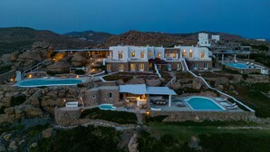 Um grande resort com várias piscinas, arquitetura em pedra e um cenário montanhoso.