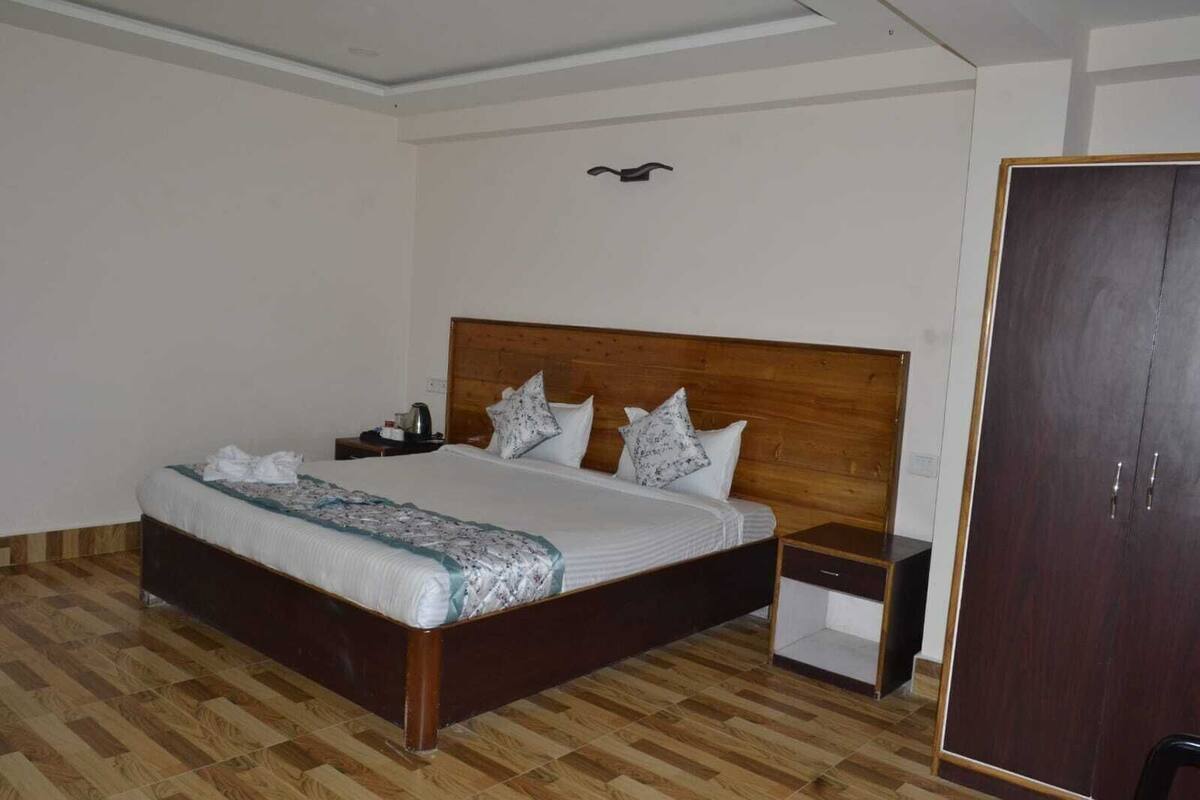 Quarto com cama de madeira, mesa de cabeceira, guarda-roupa e luminária no teto.