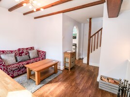 Uma sala de estar com um sofá vermelho estampado, uma mesa de centro de madeira e uma escada que leva a outro andar.