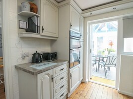 Uma cozinha com armários brancos, bancada com cafeteira, torradeira e um letreiro com a inscrição 'Glassfryn'.