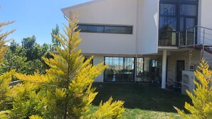 Um edifício moderno de dois andares com telhado plano, janelas amplas e uma varanda.