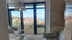 Uma sala de estar moderna com uma janela grande, um sofá, uma mesa de centro e um lustre.