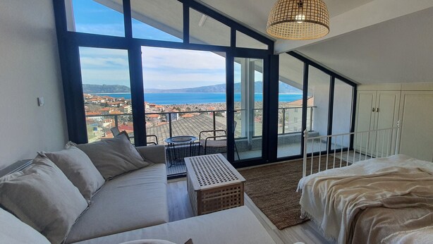 Um apartamento alto com uma varanda grande, um sofá, uma mesinha e uma cama.