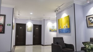 Uma área de recepção com design moderno, com um balcão de atendimento, duas portas escuras e obras de arte nas paredes.