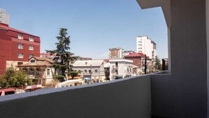 Uma varanda com vista para um horizonte urbano, incluindo edifícios e uma árvore.