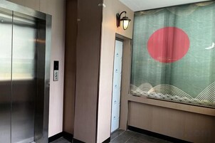 Um elevador com design moderno, luminária embutida na parede e uma janela grande com detalhe decorativo.
