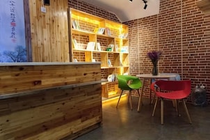 Uma área de recepção com uma mesa de madeira, uma estante e duas cadeiras.