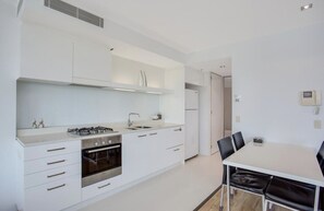 Uma cozinha moderna com armários brancos, fogão a gás e um espaço de jantar com mesa e cadeiras.