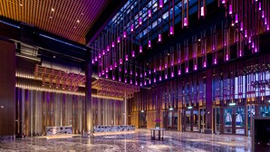 Um hall espaçoso com piso de mármore, balcão de recepção e design de teto moderno com iluminação vertical.