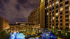 Um hotel com design moderno, apresentando uma ampla área de piscina com uma escultura azul única e uma entrada bem iluminada.