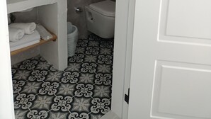 Casa de banho com lavatório branco, sanita e espelho.