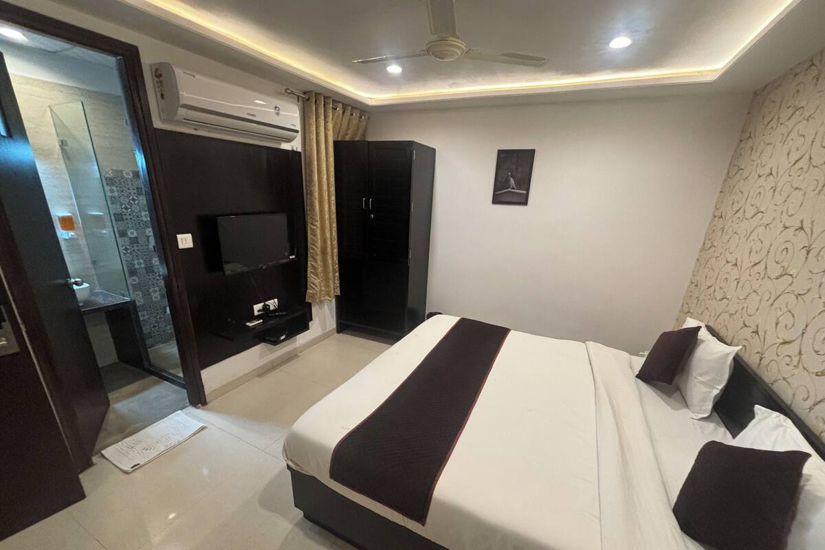 Quarto moderno com cama grande, televisão, ar condicionado e zona de duche.