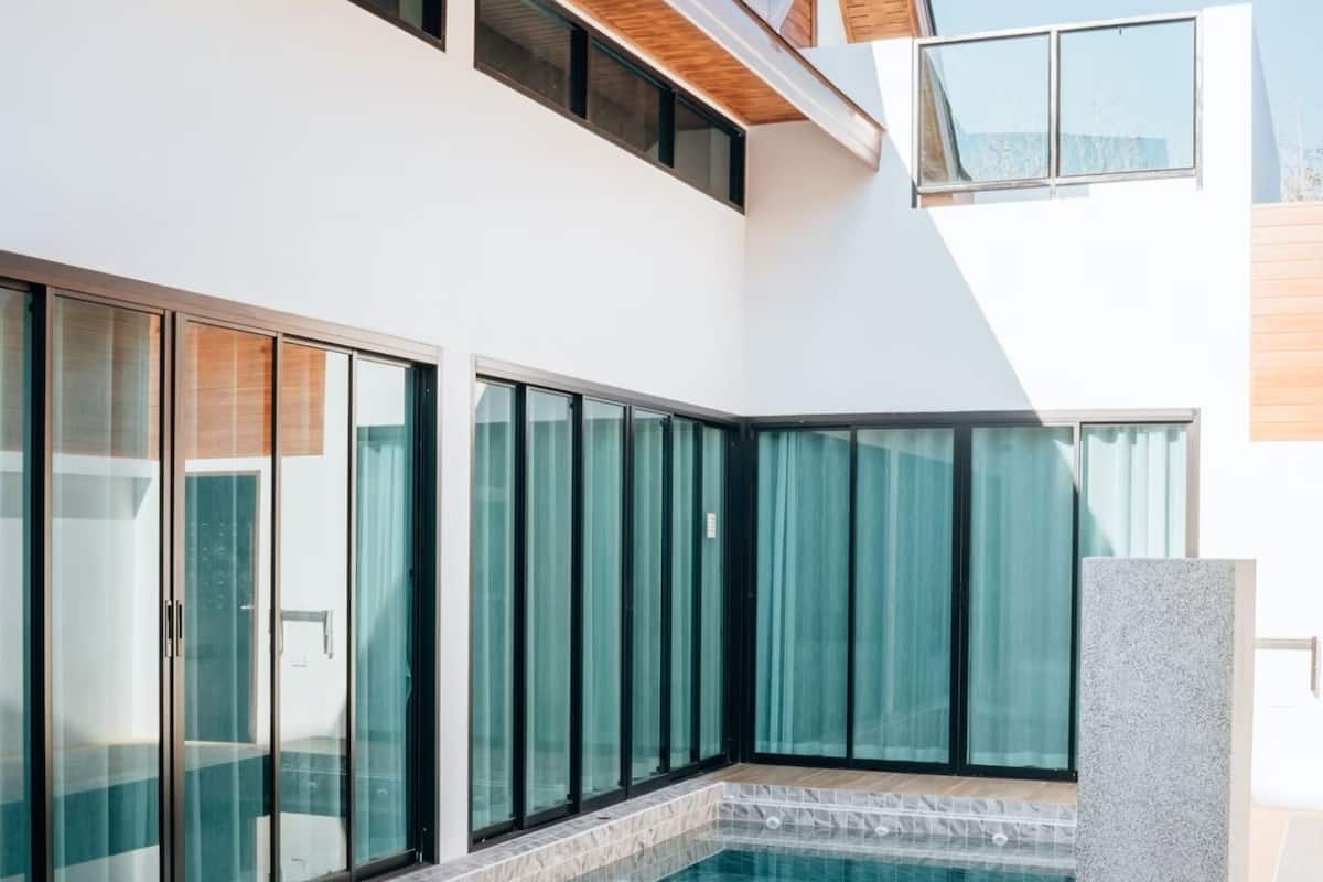 Uma casa moderna com piscina, amplas portas de vidro e um deck revestido com azulejos.