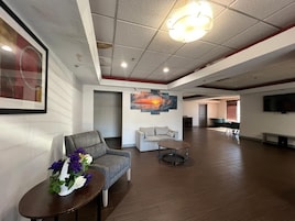 Um hall amplo com um sofá cinzento, uma mesa redonda e um quadro na parede.