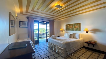 Quarto de hotel com cama, pia, janela com cortinas, teto com padrão listrado e um quadro na parede.