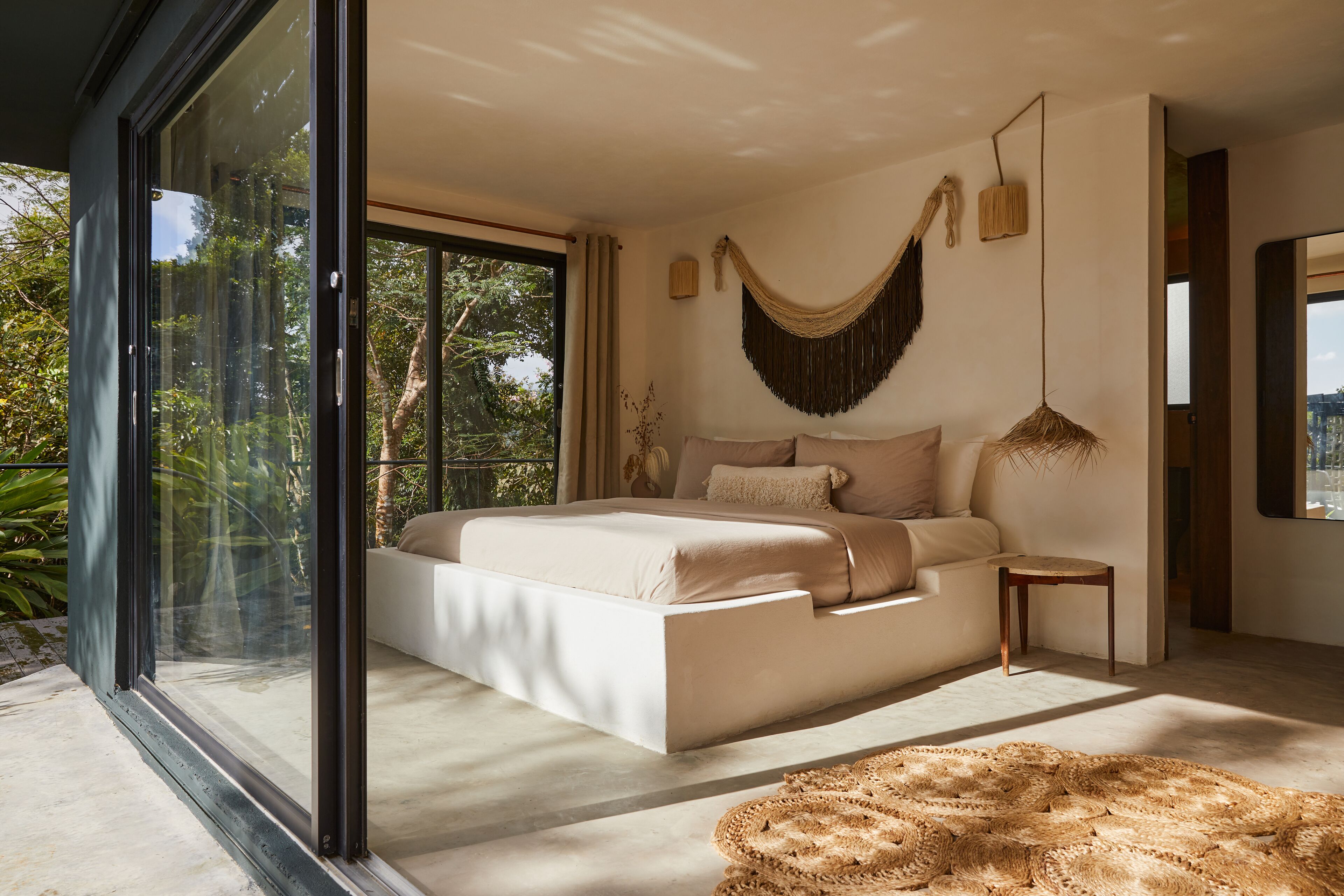 Quarto moderno com cama grande, mesinha de cabeceira e luminária suspensa.