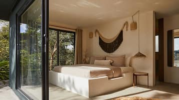 Quarto moderno com cama grande, mesinha de cabeceira e luminária suspensa.