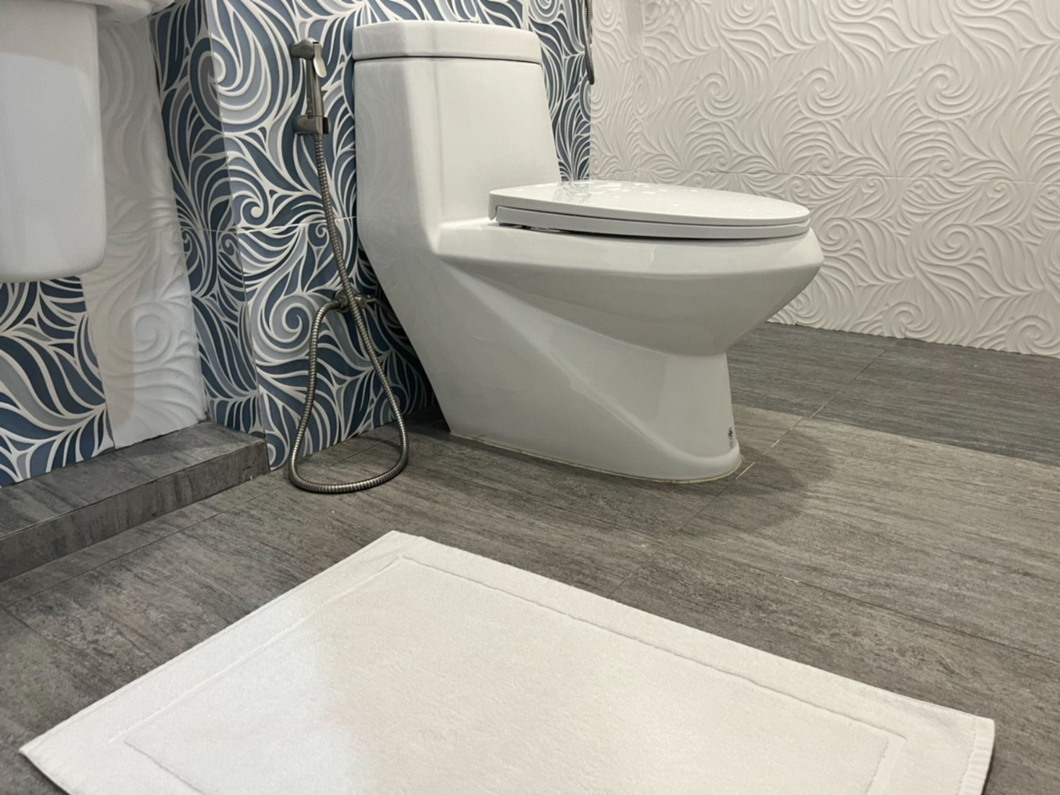 Uma casa de banho moderna com sanita, chuveiro e parede com padrão.