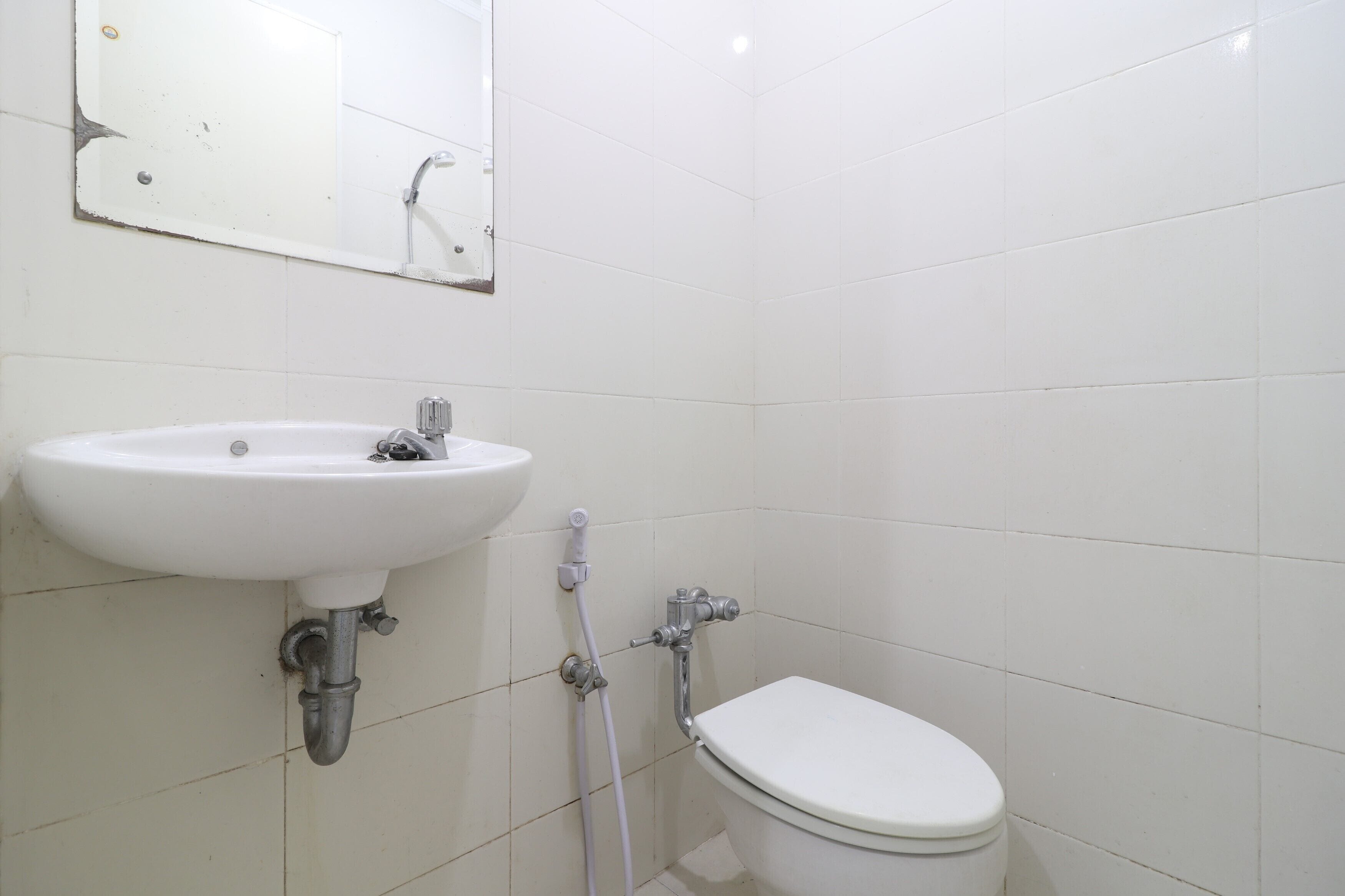 Uma casa de banho com uma pia branca, uma sanita e um espelho na parede.