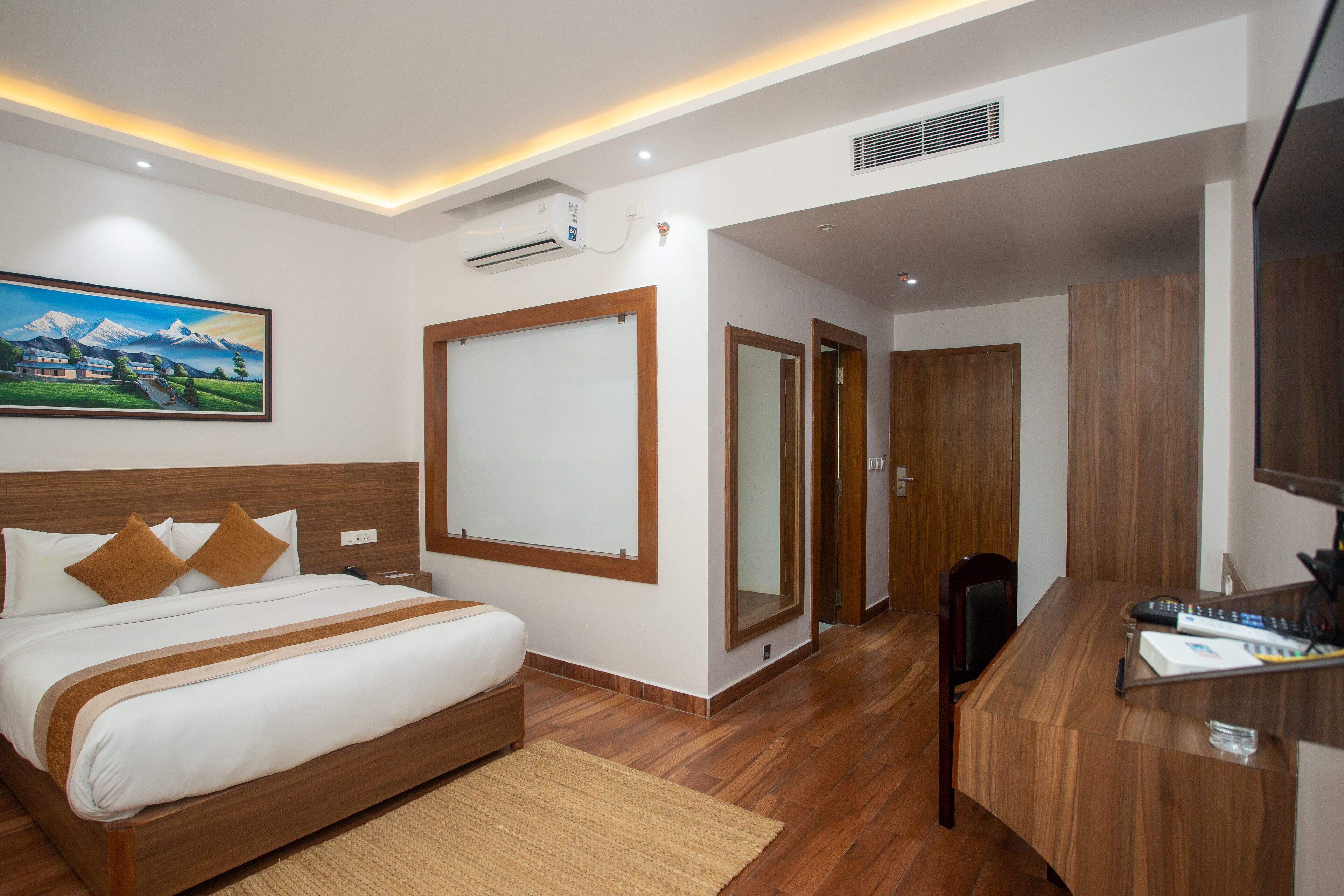 Quarto de hotel com uma cama grande, uma escrivaninha e um quadro na parede.